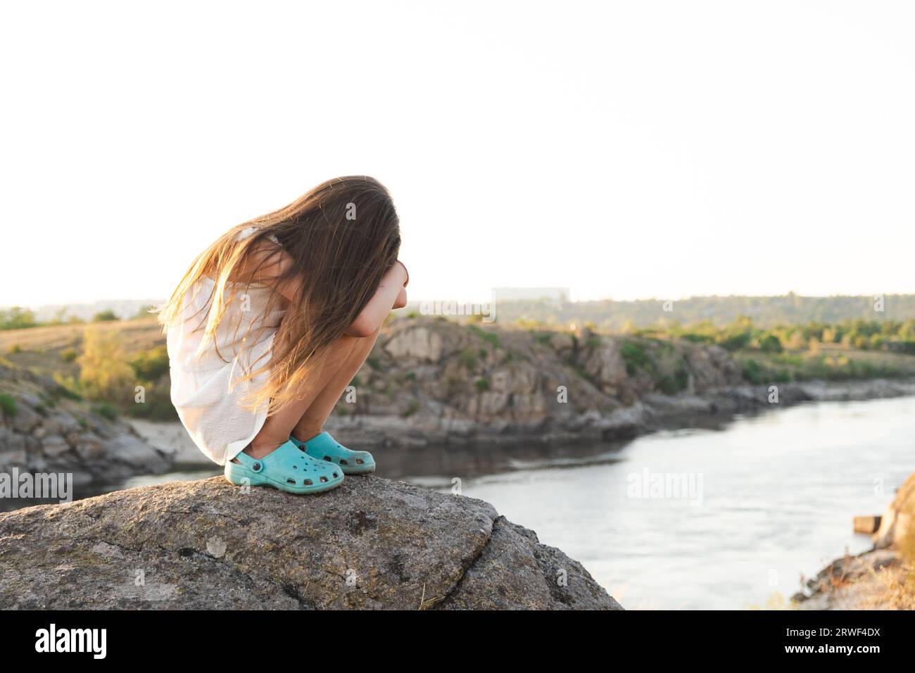 Offended five-year-old sad girl sitting on rocks in nature alone Stock ...