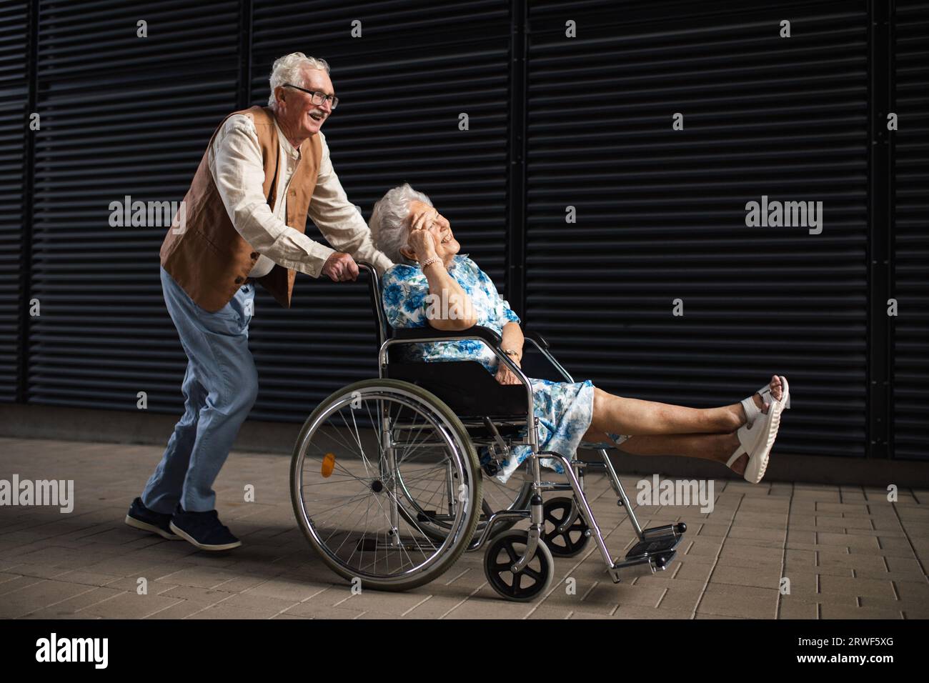 Elderly man pushing his wife in wheelchair Stock Photo - Alamy