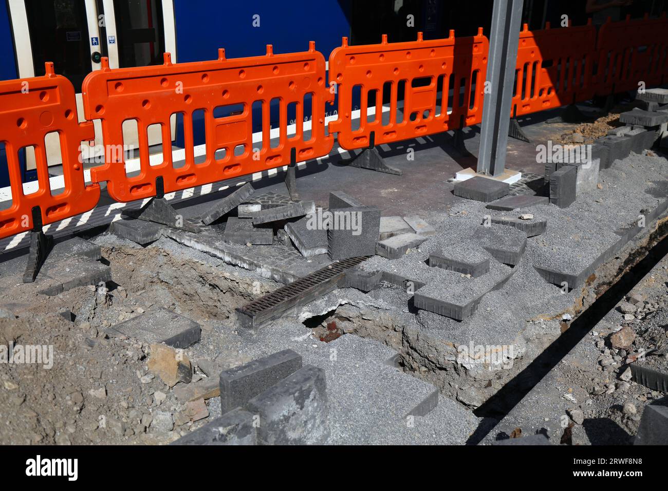 Concrete paver resurfacing works at a railway station platform. Rain ...