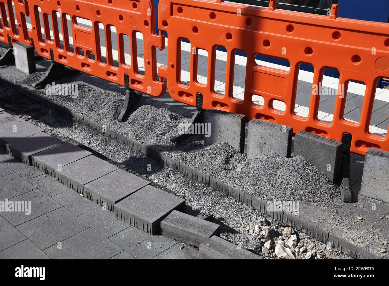 Concrete paver resurfacing works at a railway station platform. Rain ...