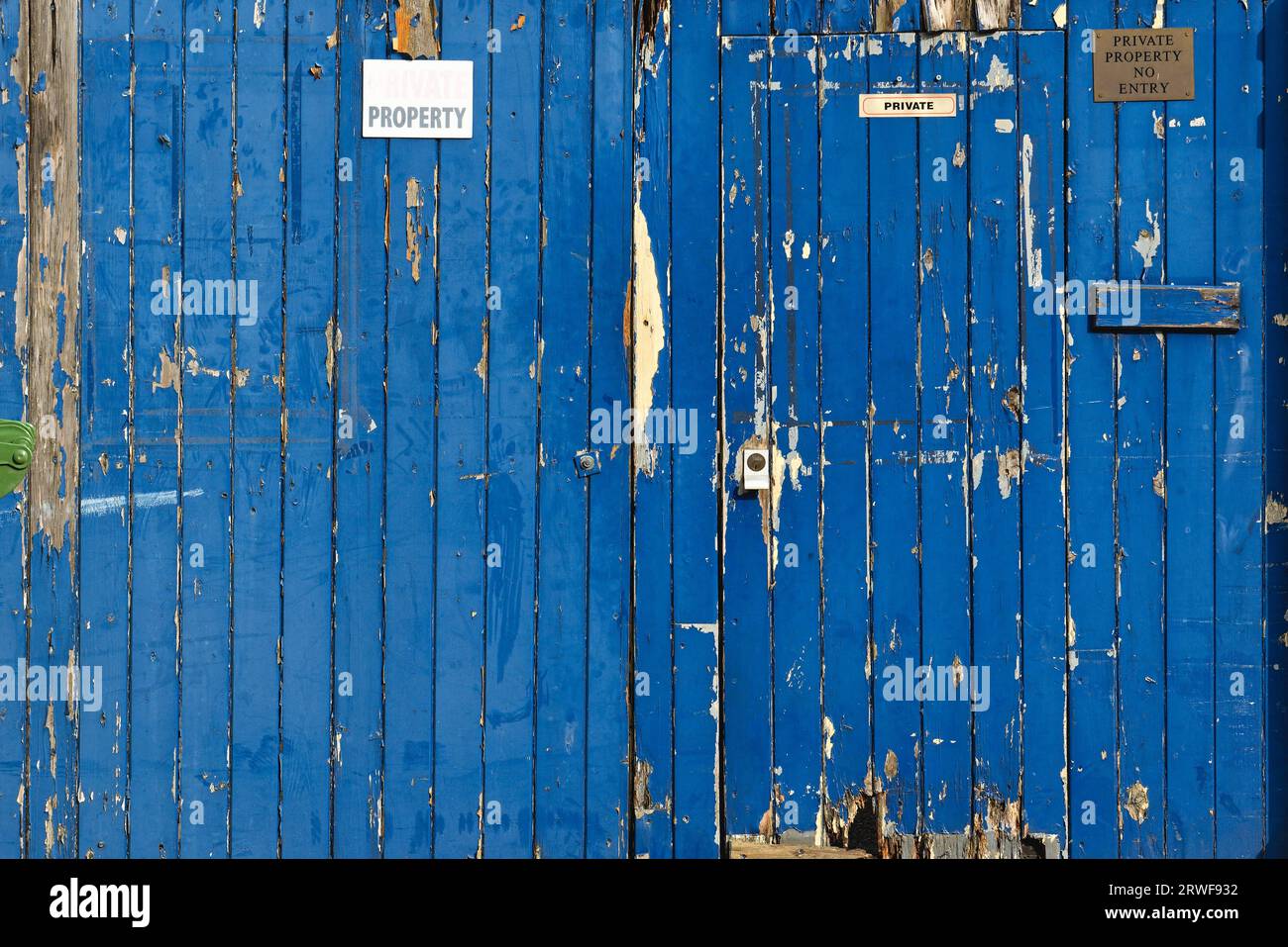 Detail of a dark blue wooden gate with peeling paint creating an ...