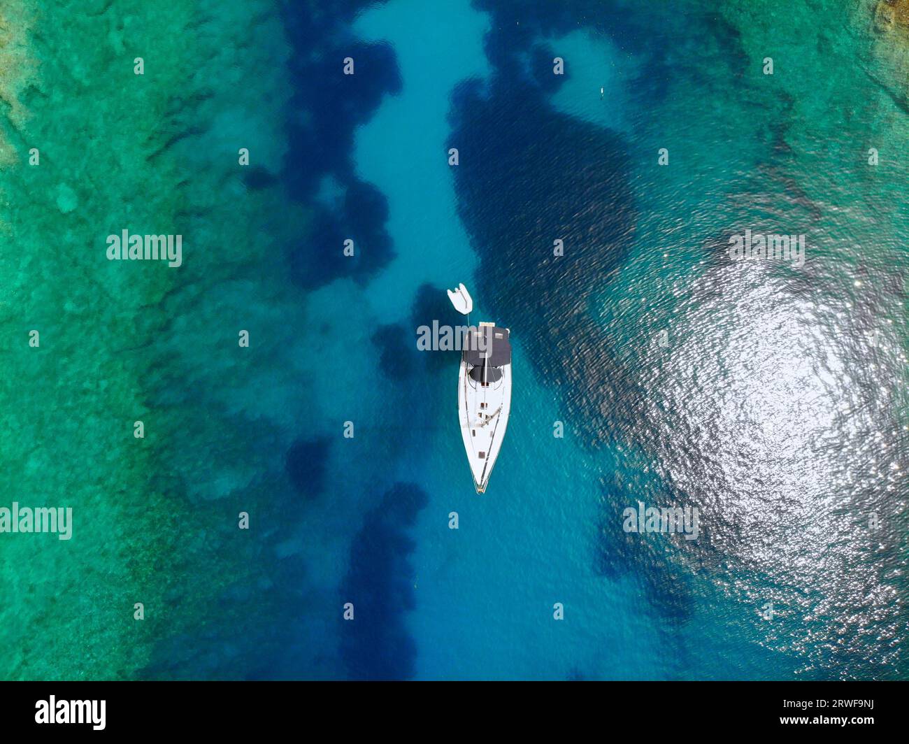 Paradise cove with white sailboat towing a dinghy - Rasohatica bay of ...