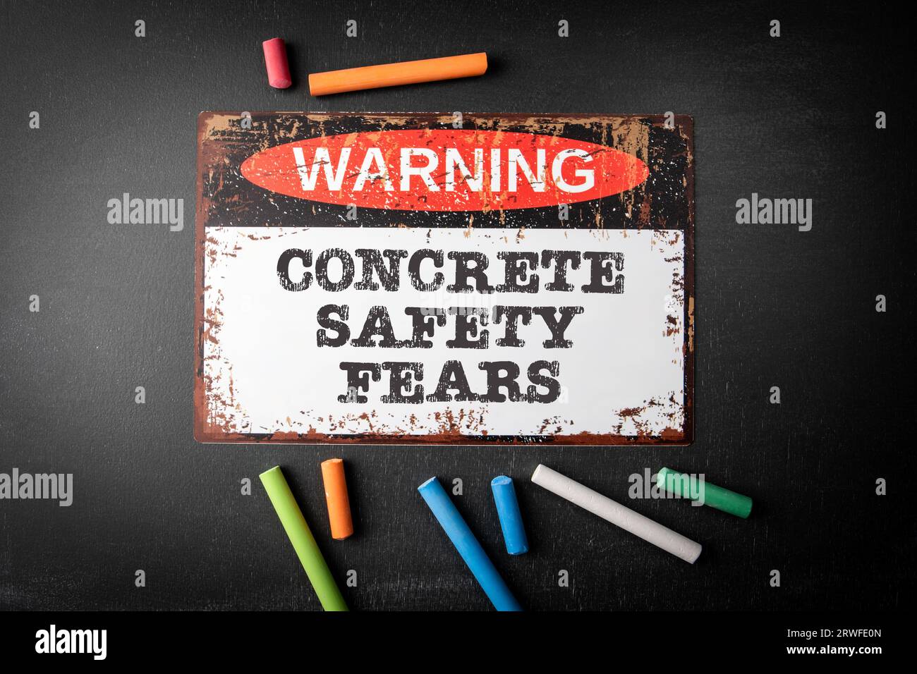 Concrete safety fears. Metal warning sign and colored pieces of chalk ...