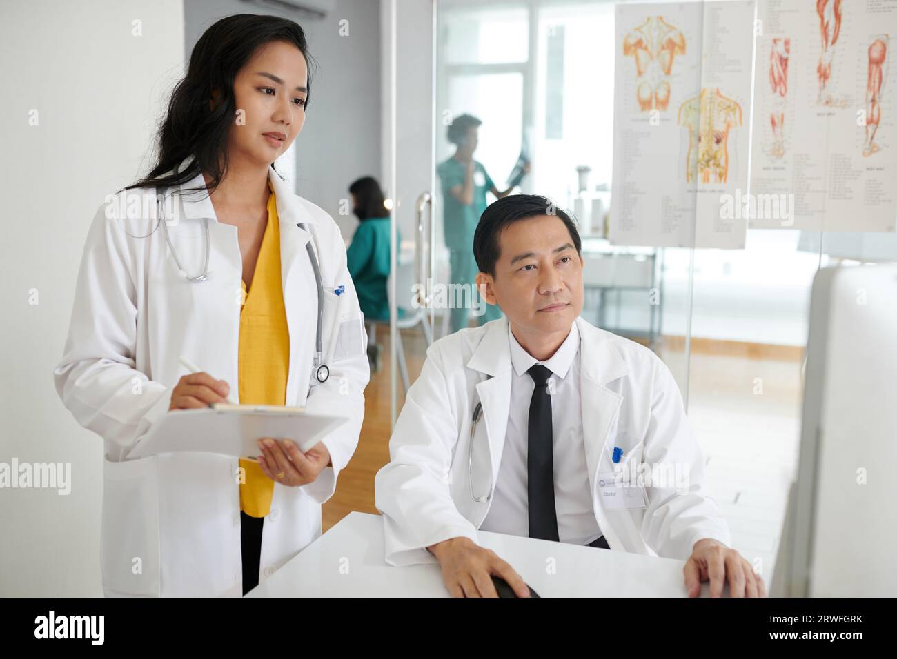 Doctors checking results of patients medical tests and filling form ...