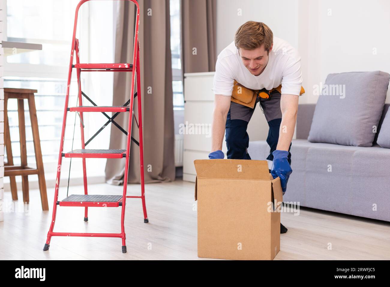 Young man holding cardboard package working in warehouse among racks ...