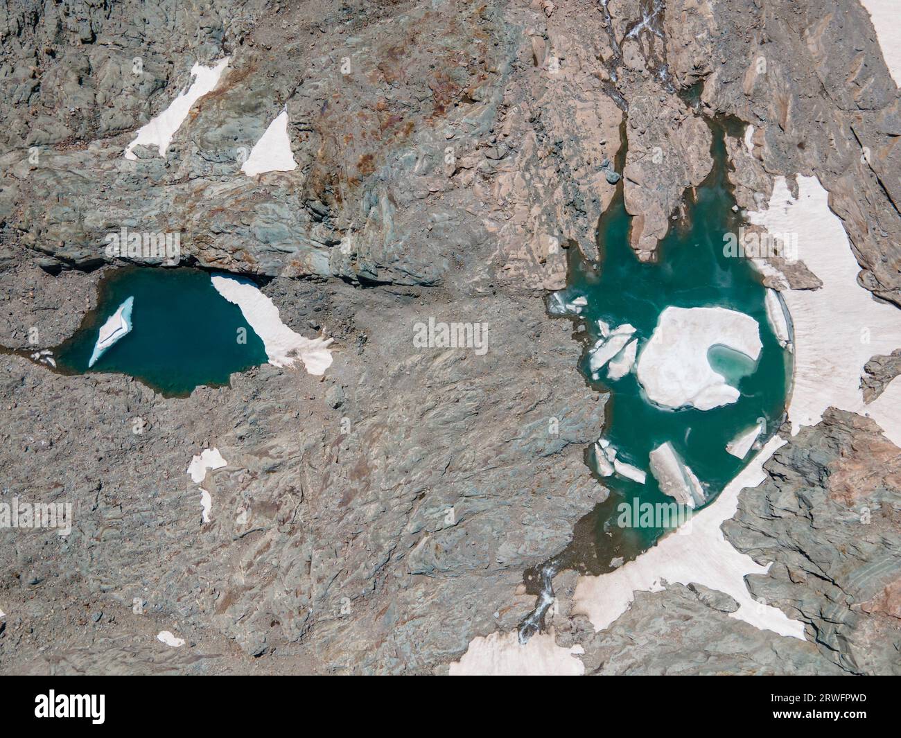 drone aerial top down view of glacial lakes in the mountain with frozen water and icebergs ...