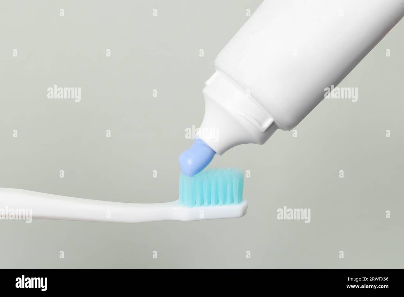 Applying paste on toothbrush against grey background Stock Photo - Alamy