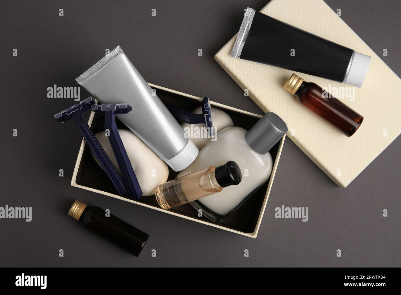Different men's shaving accessories and box on dark grey background ...