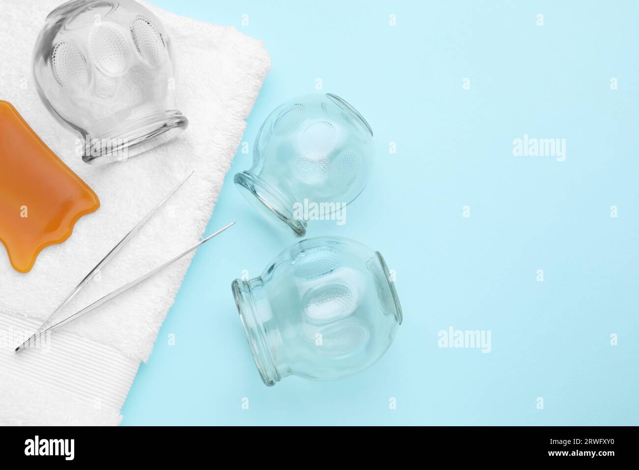 Glass cups, towel, tweezers and gua sha on light blue background, flat ...
