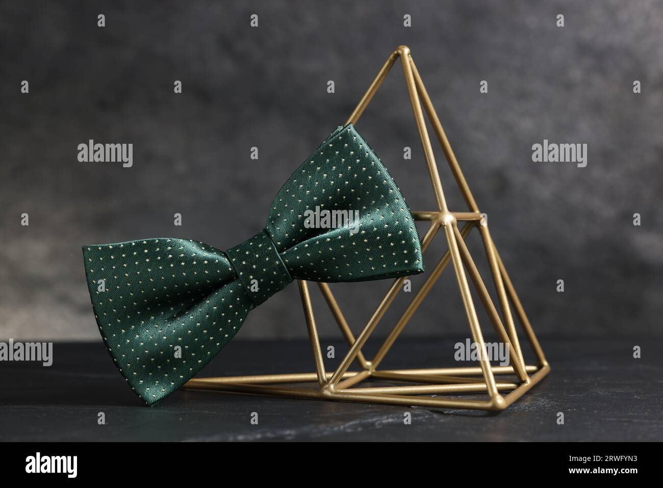 Stylish presentation of green bow tie on black table against gray ...