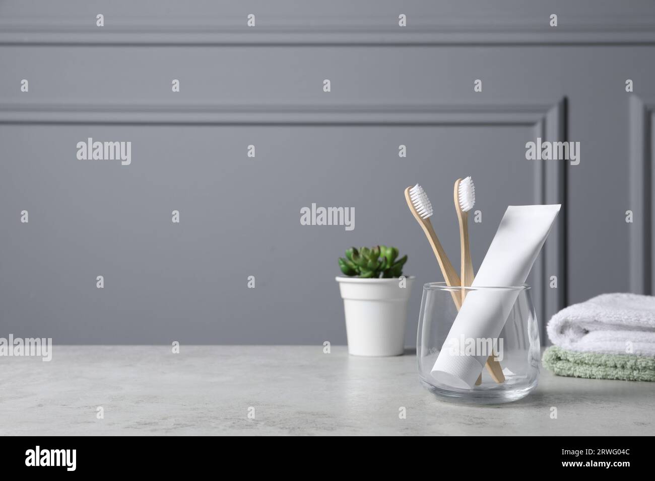 Bamboo toothbrushes in holder, toothpaste, houseplant and towels on ...