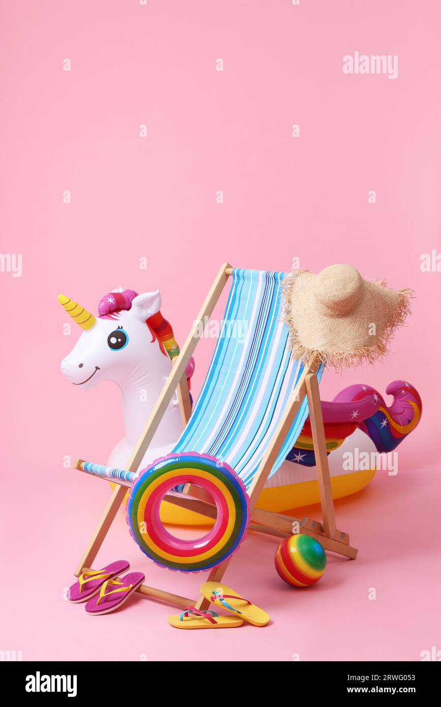 Deck chair, flip flops and other beach accessories on pink background ...