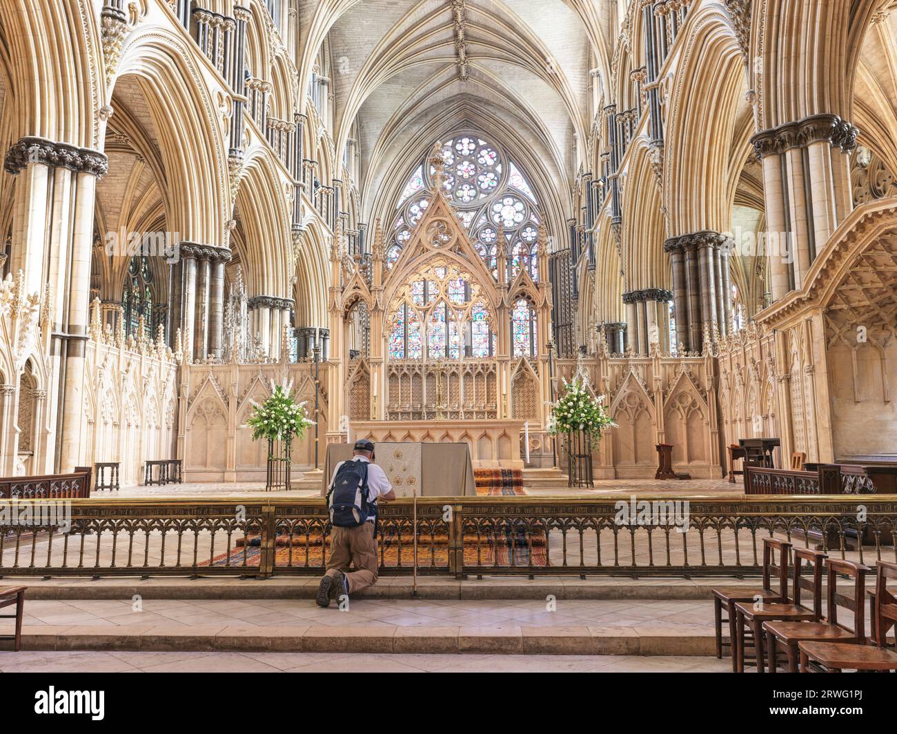 Man kneeling in prayer before the altar at the chancel of the norman ...