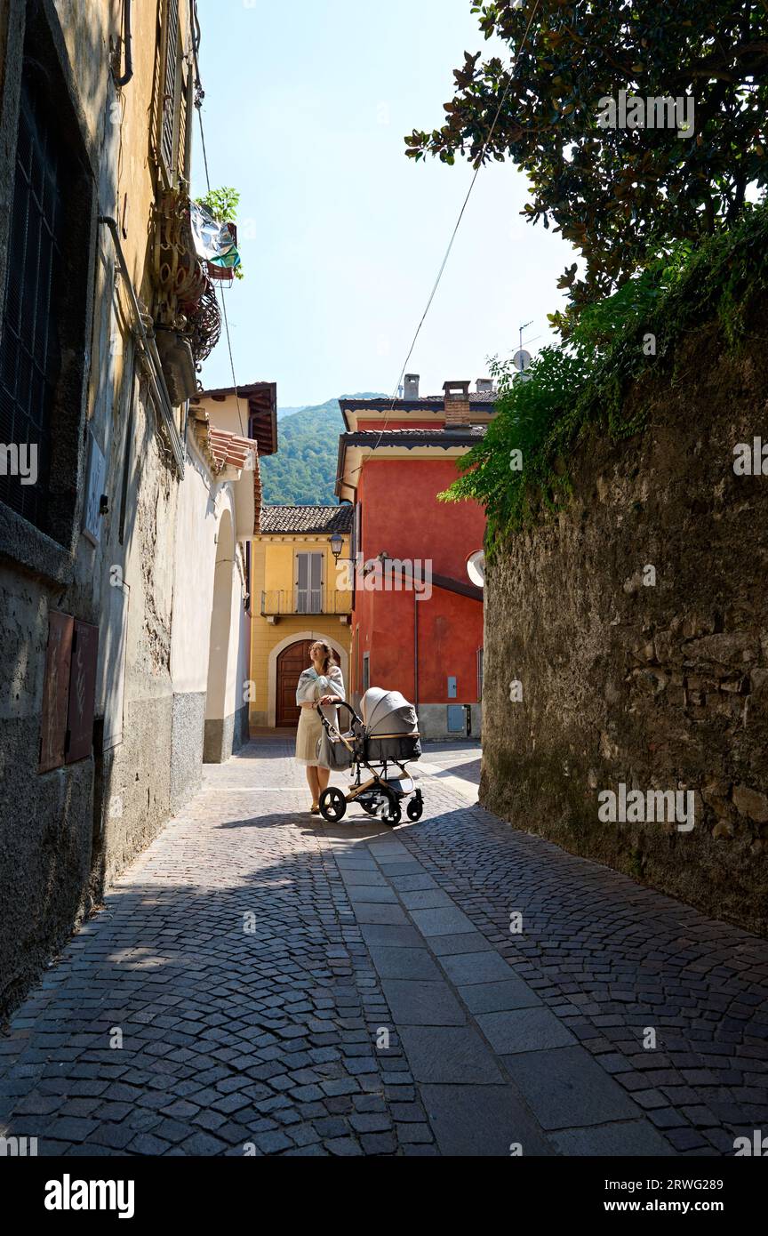 Beautiful mother pushing a stroller with sleeping baby, walking along a ...