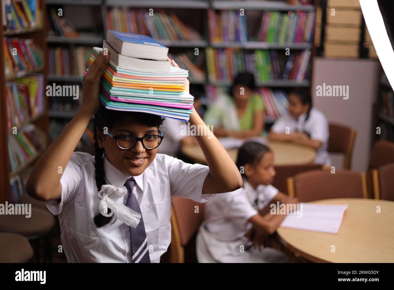 Happy teenager girl student holding books on her head, standing in ...