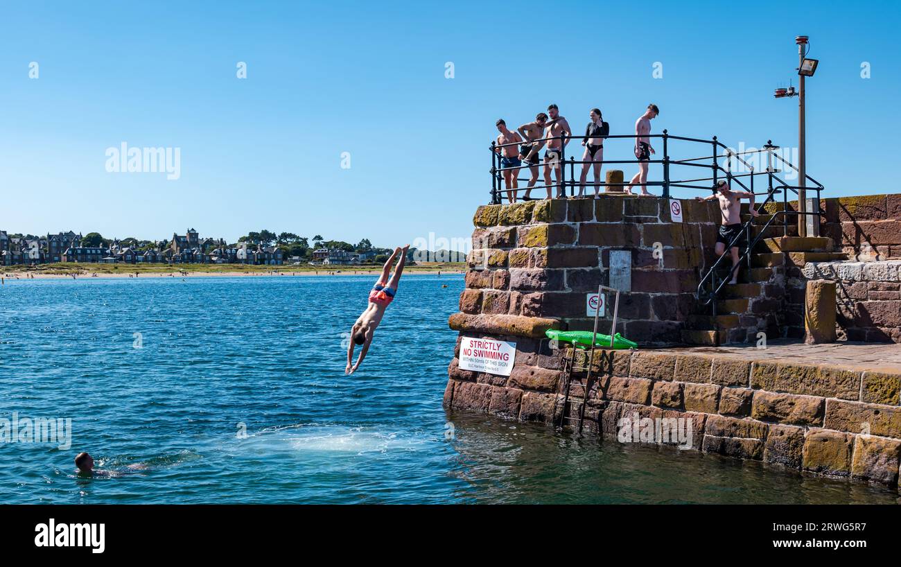 Boy diving into sea from quayside in hot Summer weather, North Berwick ...