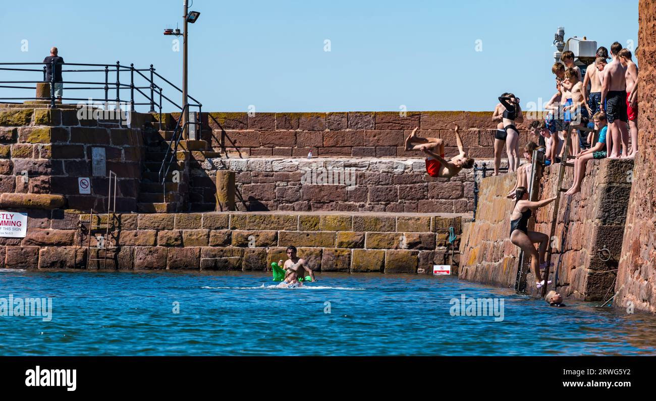 Children jumping into sea from quayside in hot Summer weather, North ...