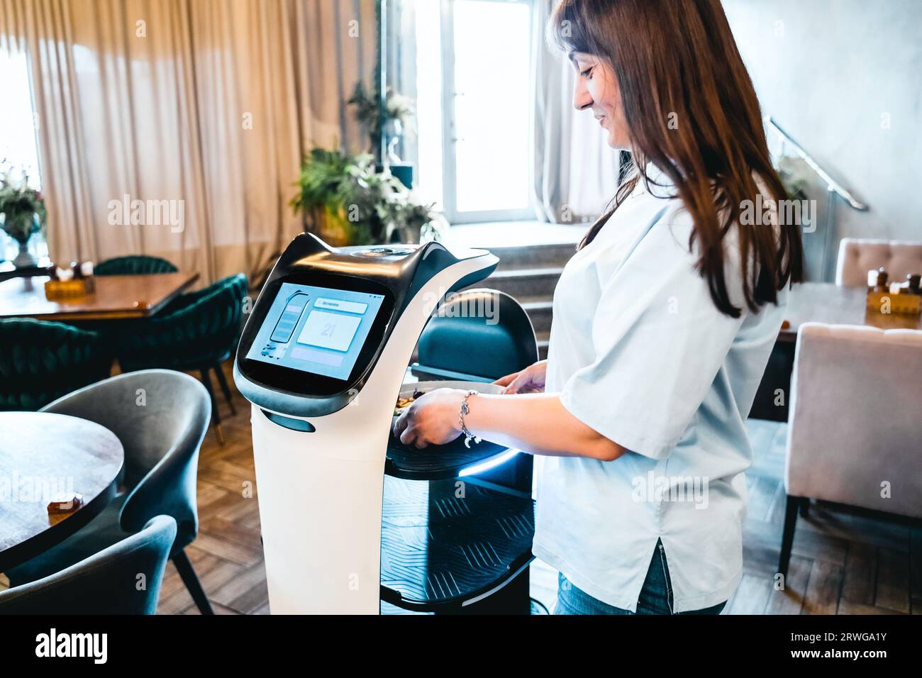 Robot waiter serve food at modern restaurant table.Offering innovation ...