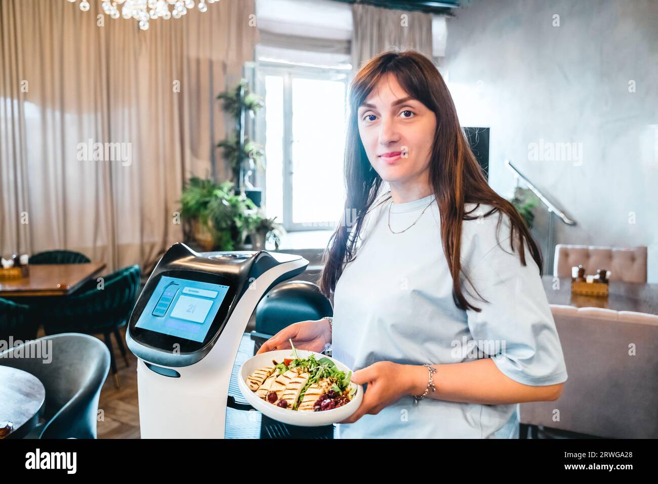 Robot waiter serve food at modern restaurant table.Offering innovation ...