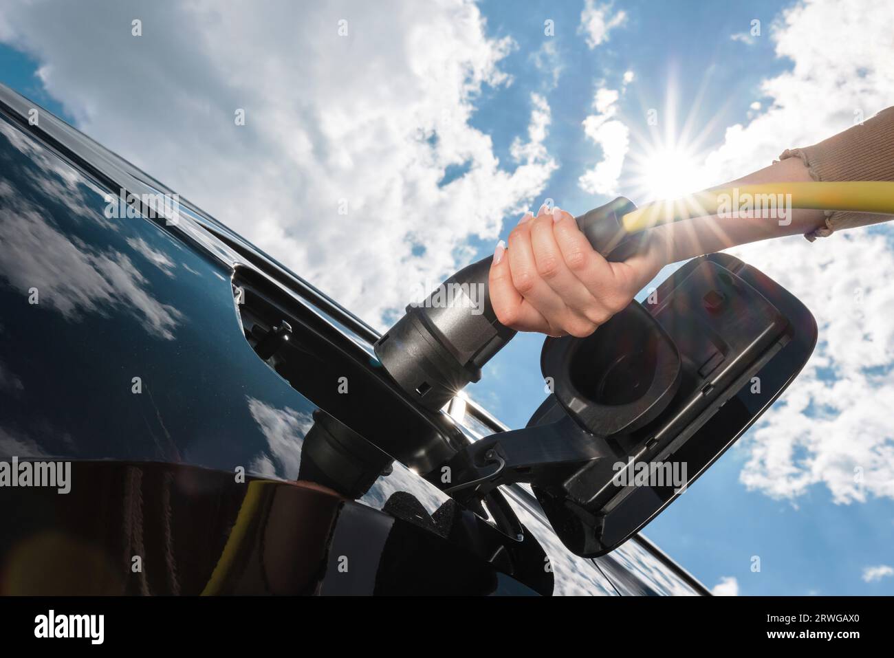 Female hand charging electric car with blue sky, photo from below Stock ...