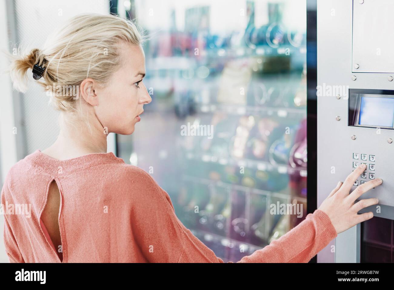 Caucasian woman using a modern vending machine. Her right hand is ...
