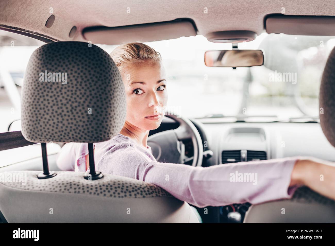 Beautiful young lady looking back through the rear window from the ...