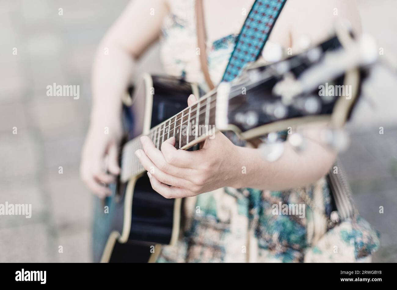 Female street musician playing guitar on sidewalk Stock Photo - Alamy