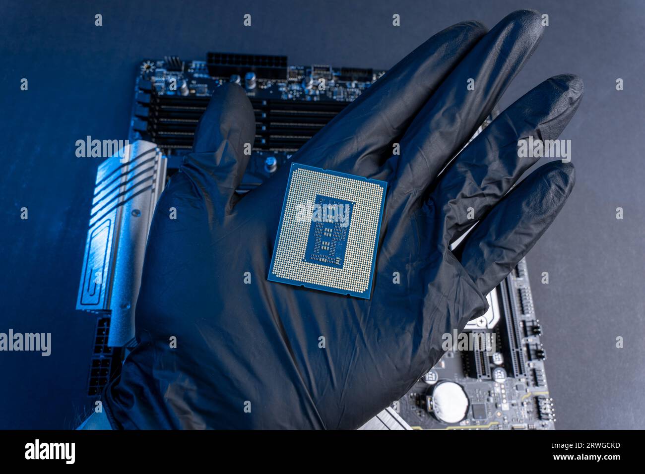 The engineer's gloved hand holds the CPU chip against the background of ...