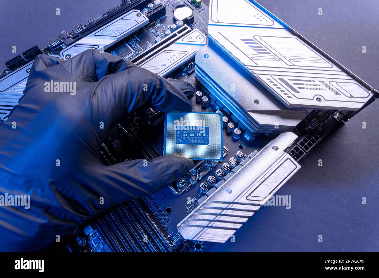 The engineer's gloved hand holds the CPU chip against the background of ...