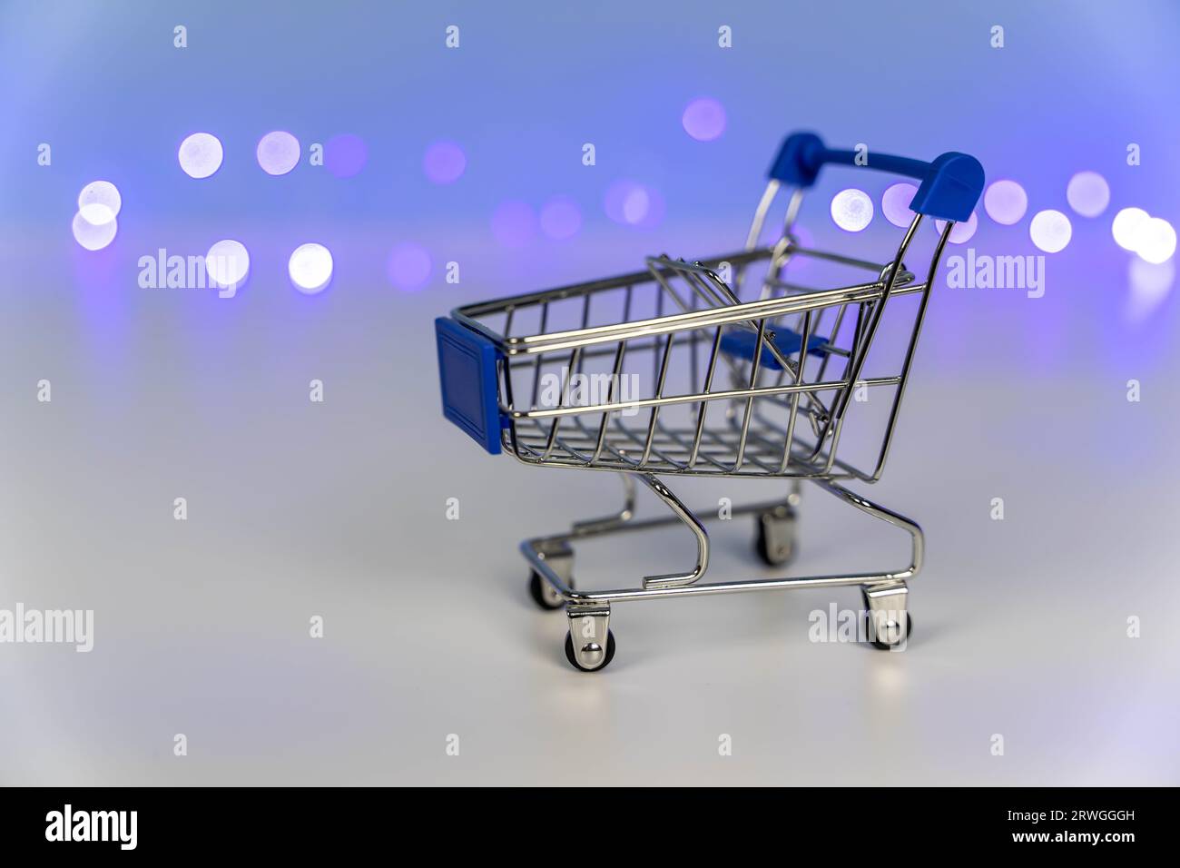 An empty supermarket cart on a blue background with blurry lights ...