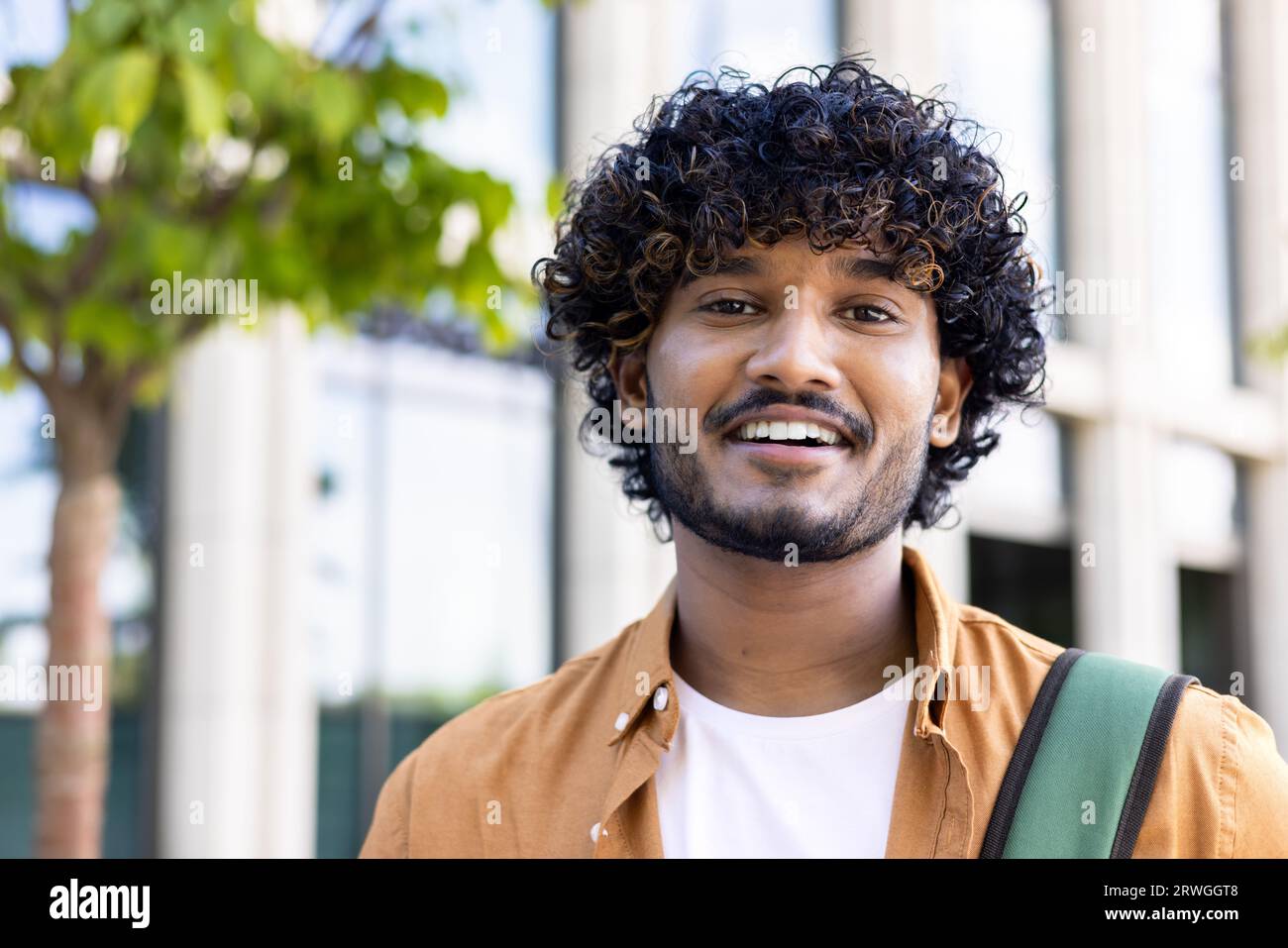Close-up photo of a young Indian man wearing an orange shirt and ...