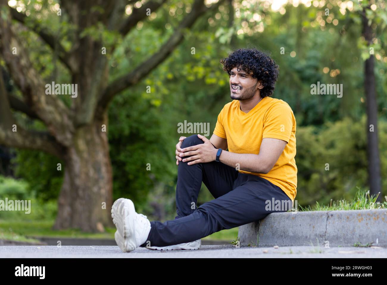 A young Indian man does sports in the park, takes a morning walk. Got a ...