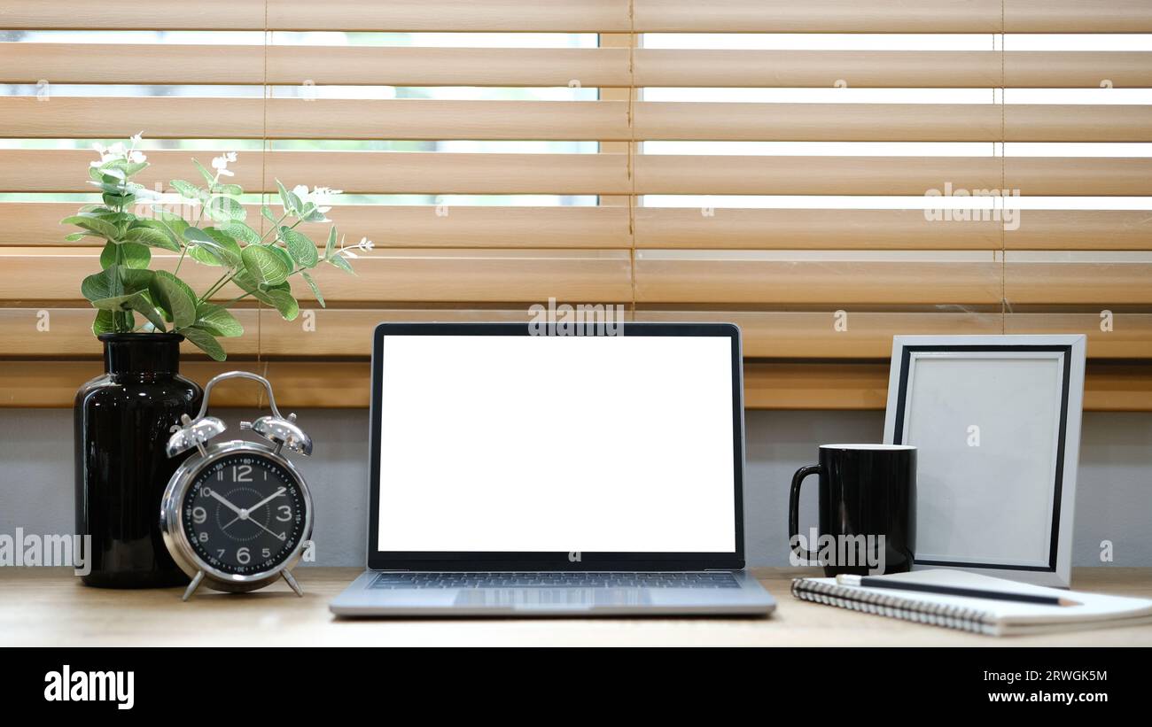 White laptop with blank screen placed on table near window Stock Photo ...