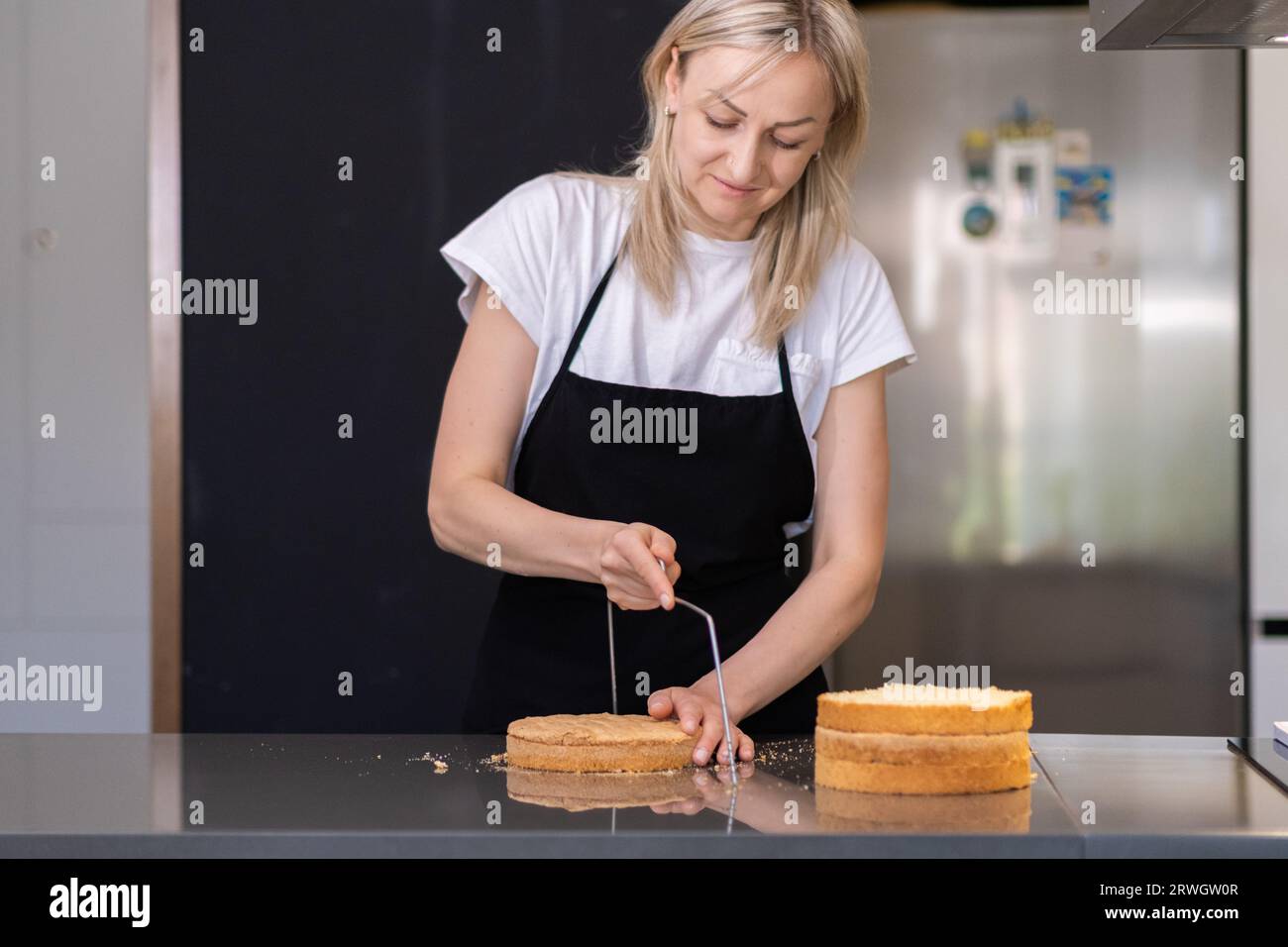 Focused blonde housewife showing tutorial of cutting baked cake with string knife Stock Photo ...