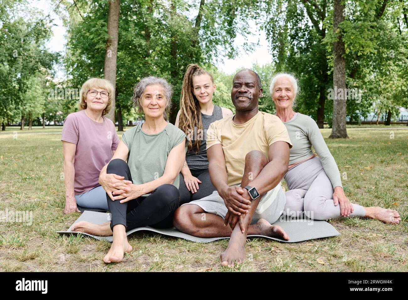 Portrait of senior people sitting on the grass with their coach and ...