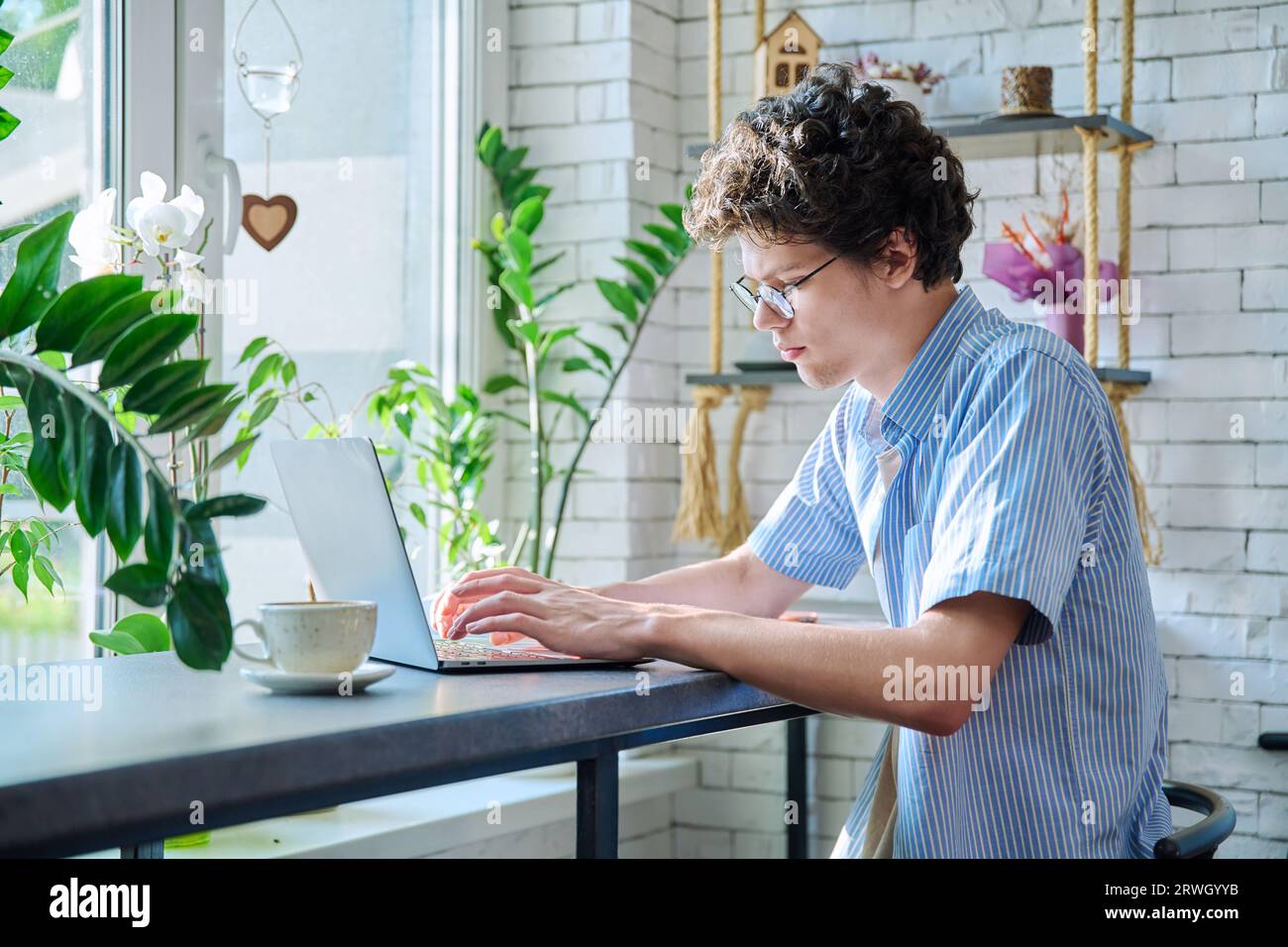 Young guy is university student typing on laptop, sitting in coffee ...