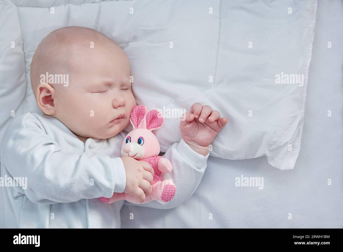 Cute baby sleeps with his toy knitted pink bunny. The concept of a new ...
