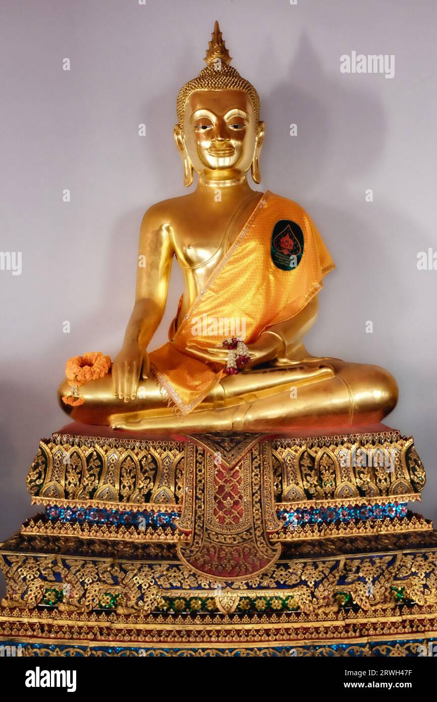 A golden Buddha statue sitting in the lotus position on a pedestal ...