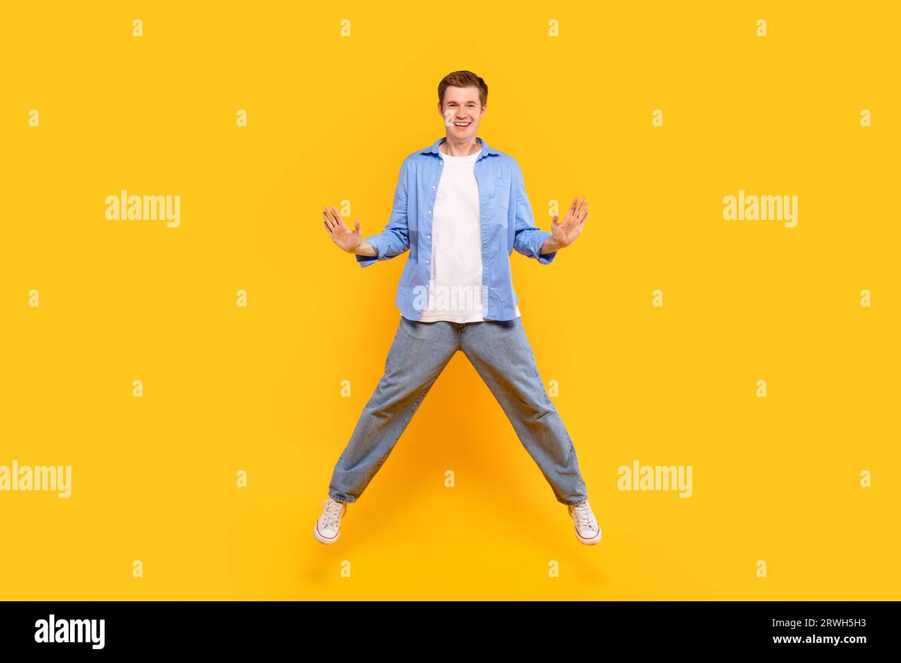 Joyful caucasian guy jumping smiling to camera posing over yellow ...
