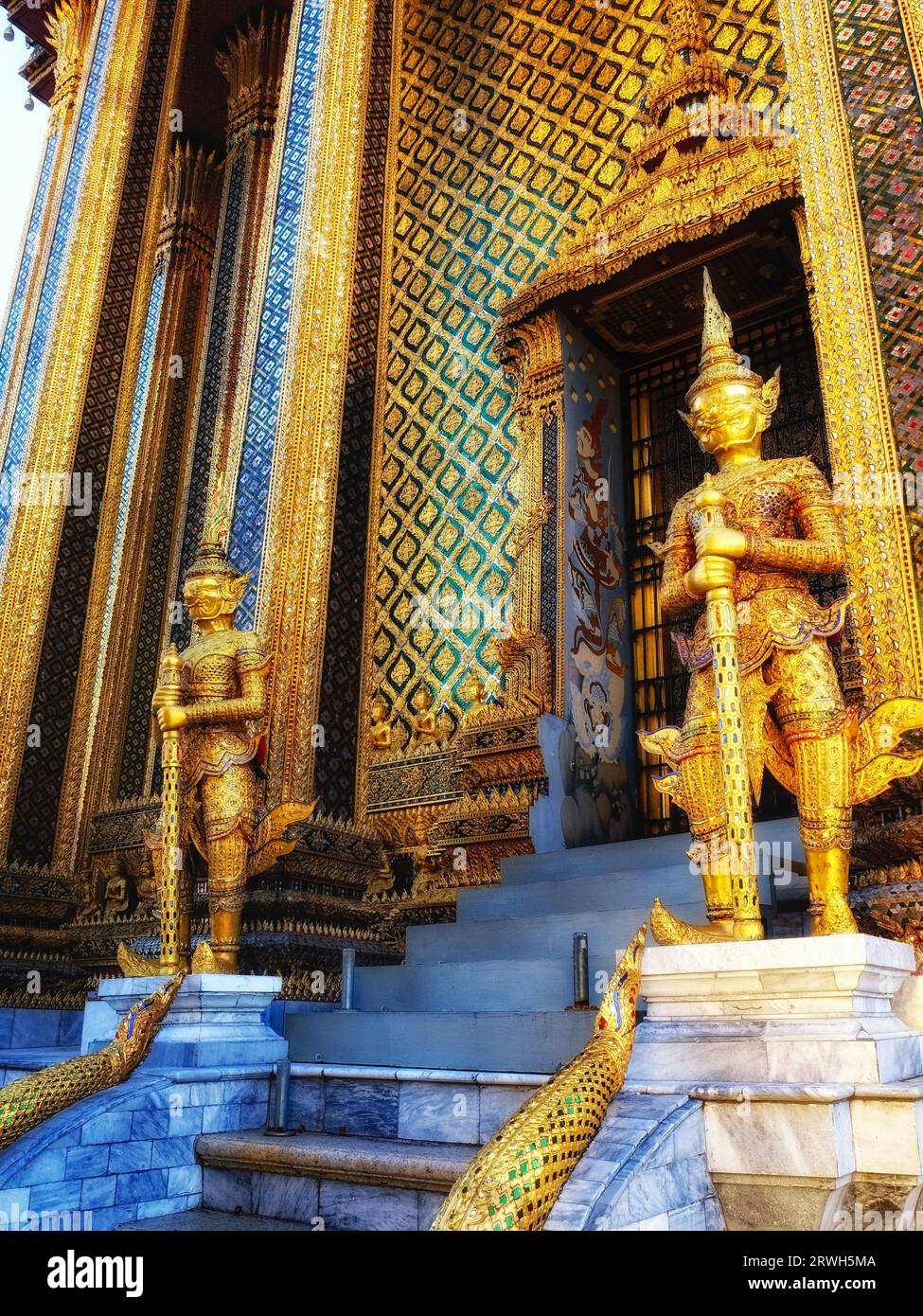 A pair of gilded sculptures depicting demons wielding weaponry stand ...