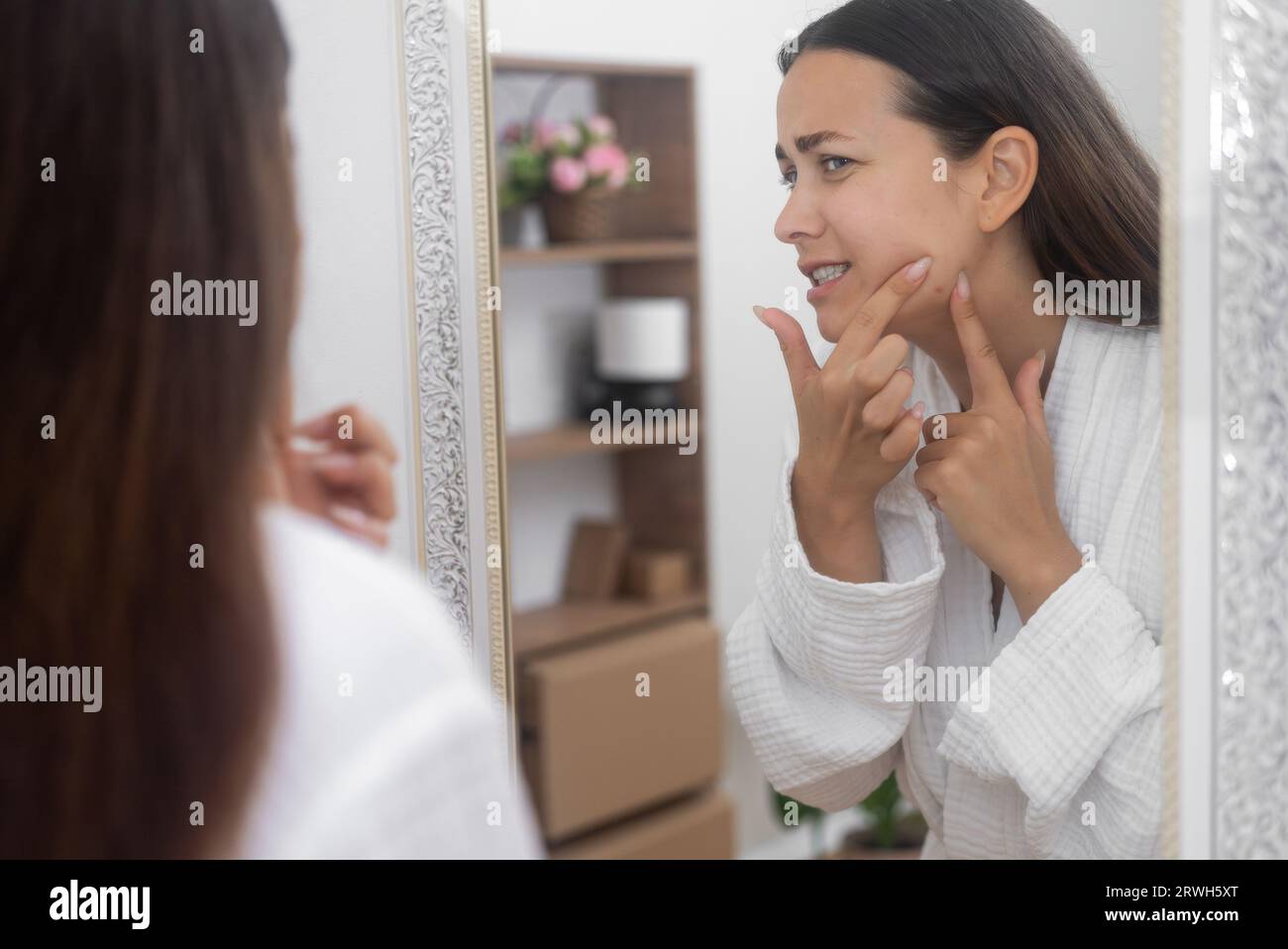 Upset woman popping pimple looking in mirror in bathroom emotional lady ...