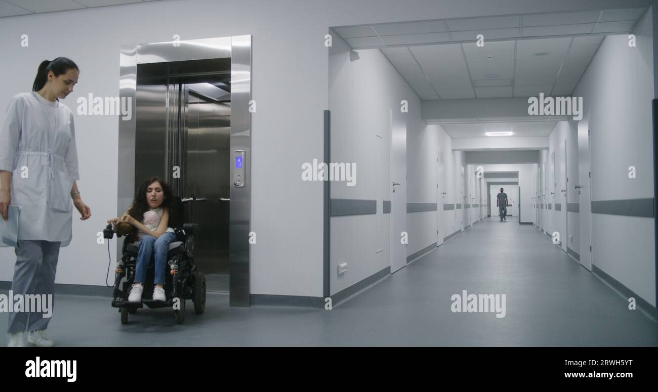 Woman in motorized wheelchair leaves elevator with doctor, rides along ...