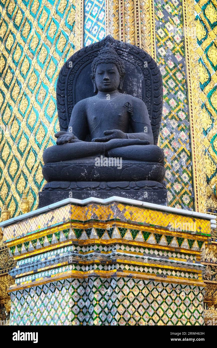 A serene Buddha statue. The dark statue, seated on a base, is placed ...