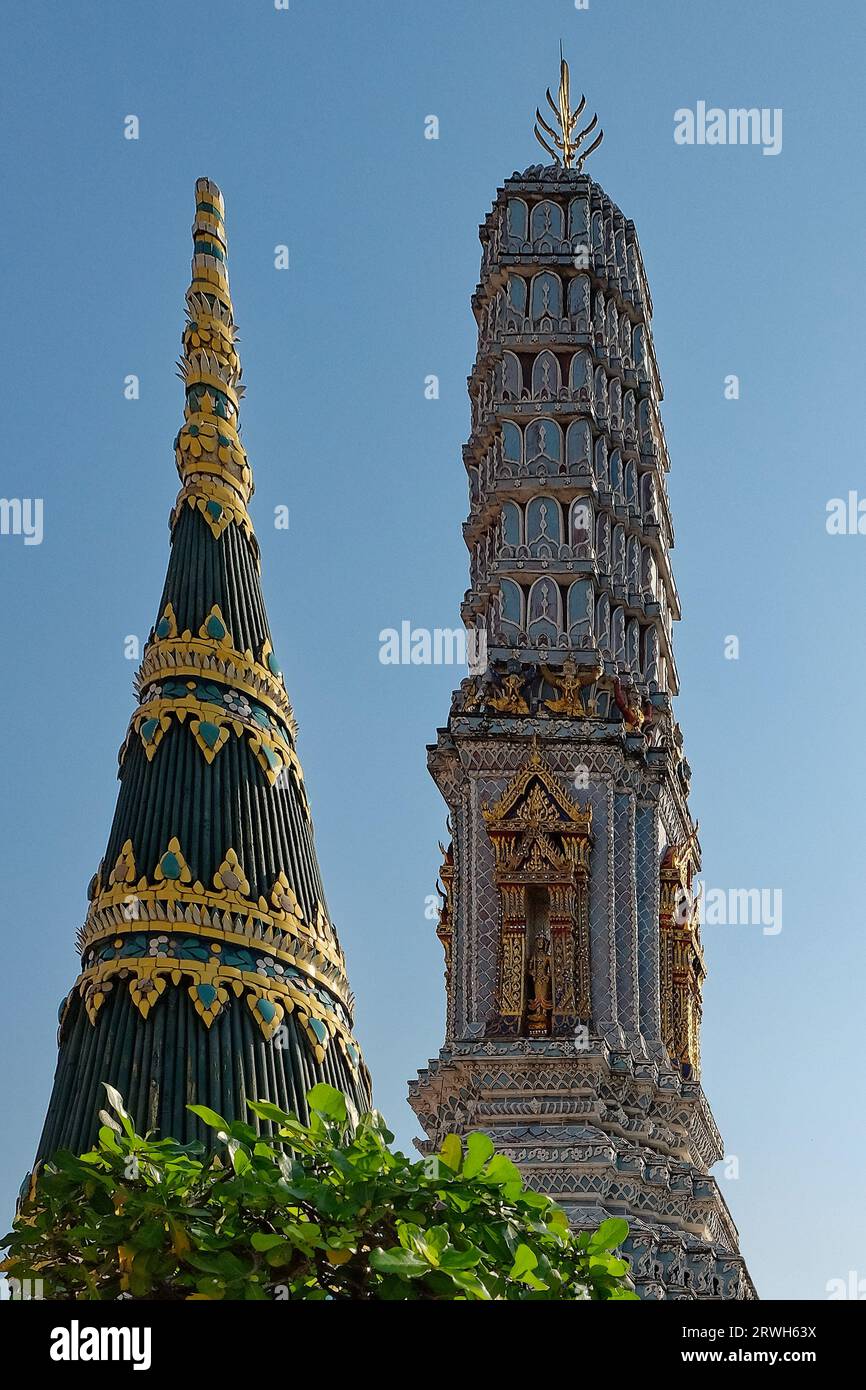 Two ornate temple spires in Thailand, intricately decorated in gold and ...