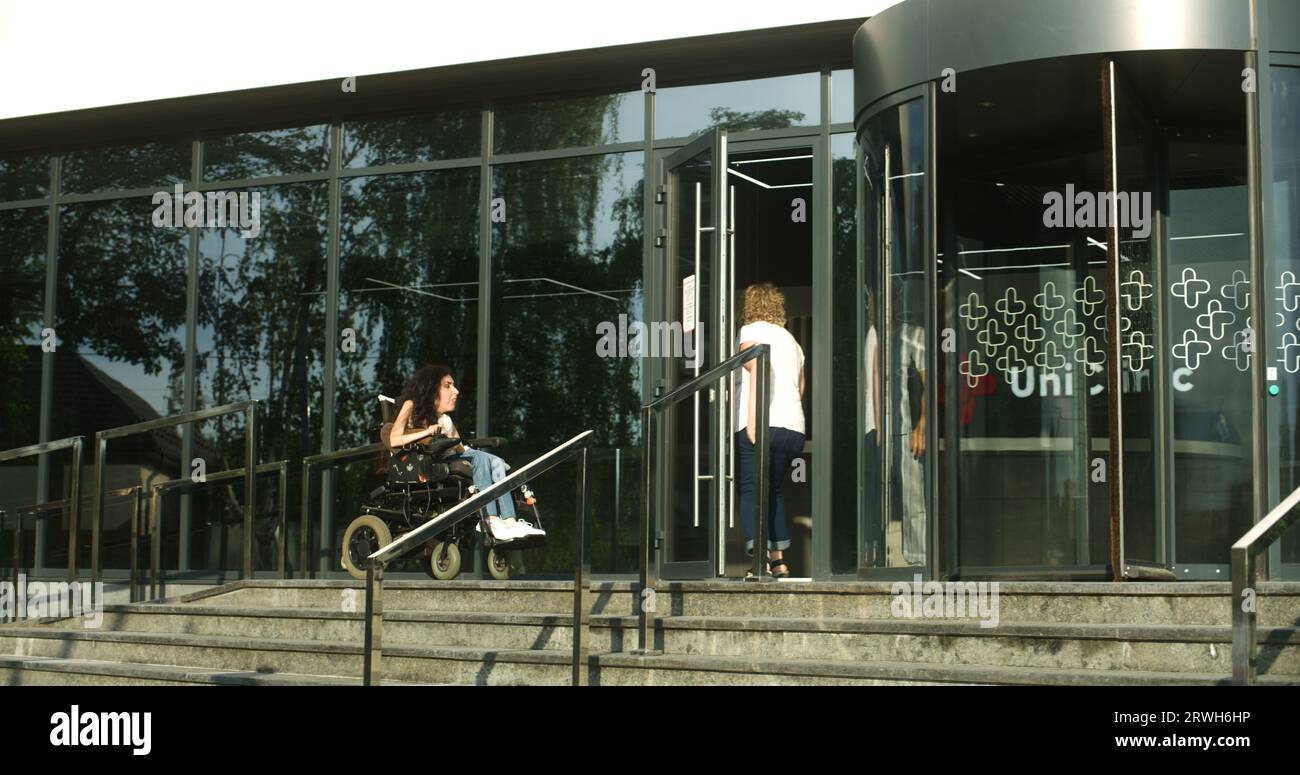 Woman with physical disability rides into clinic entrance on motorized ...