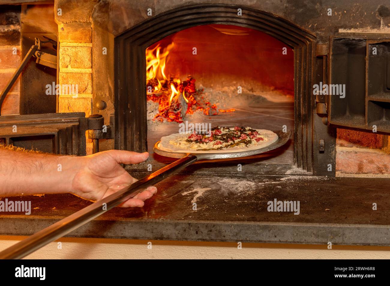 Hand of pizzailo puts pizza on a shovel in traditional wood-fired oven Stock Photo - Alamy