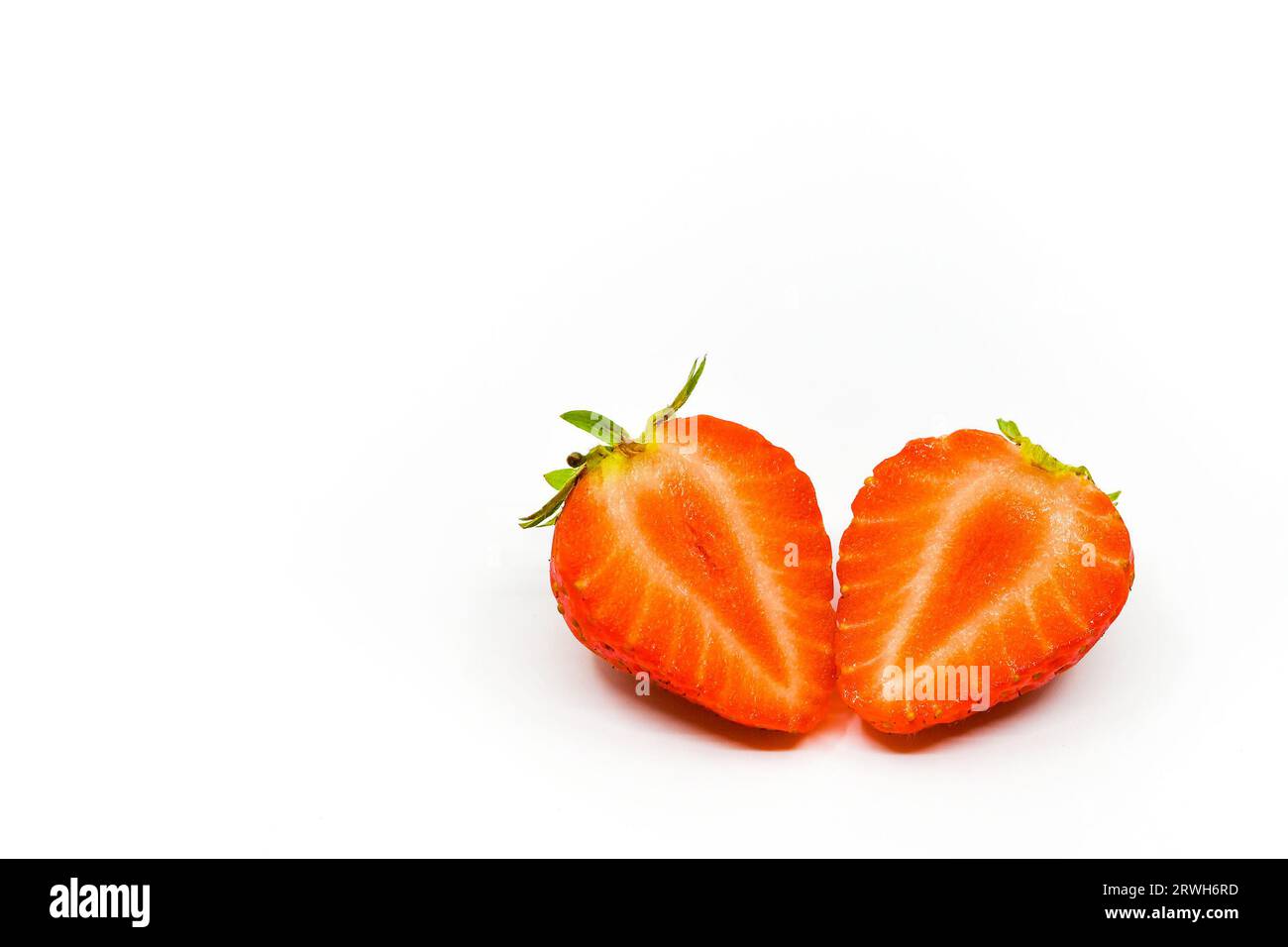 Fresh ripe strawberry cut in half on a plain white background. Copy ...