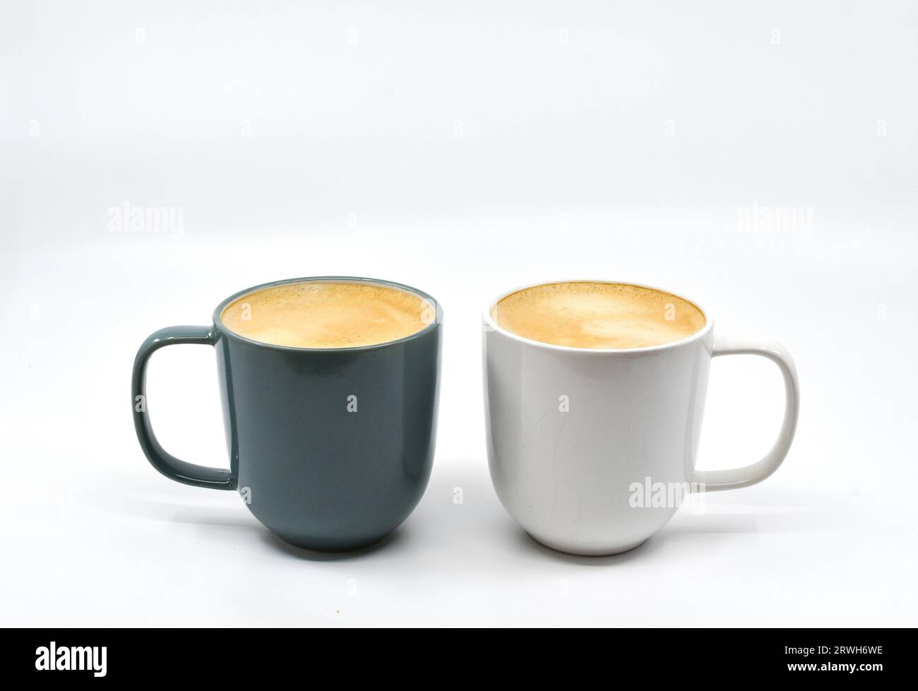 Two mugs of hot frothy coffee isolated on a plain white background ...