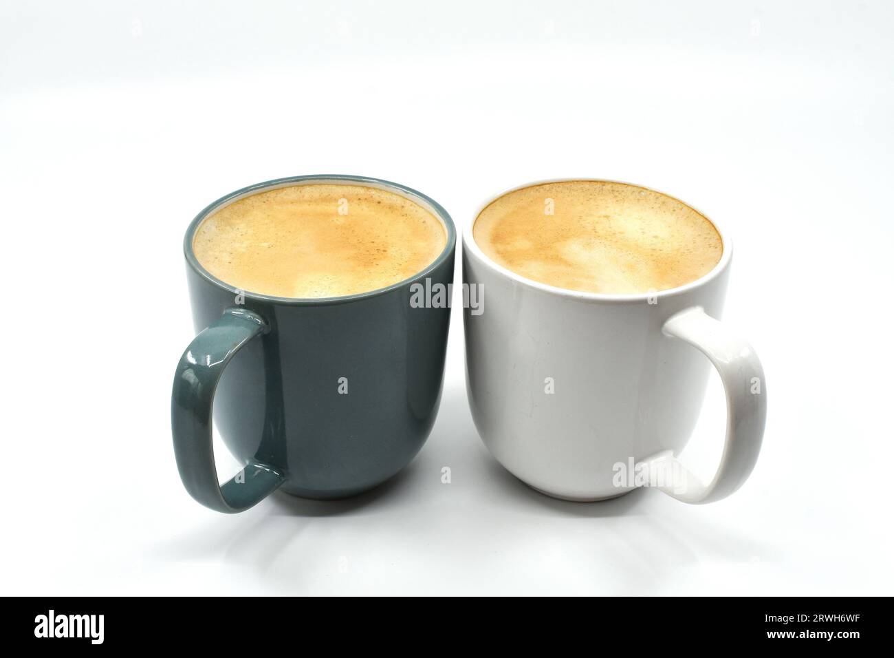 Two mugs of hot coffee in contrasting coloured mugs isolated on a plain ...