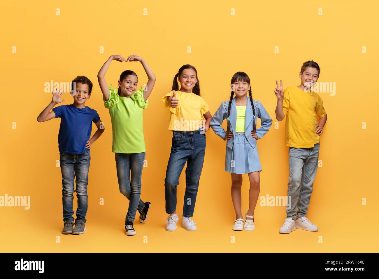 Positive adorable diverse children grimacing and gesturing on yellow ...